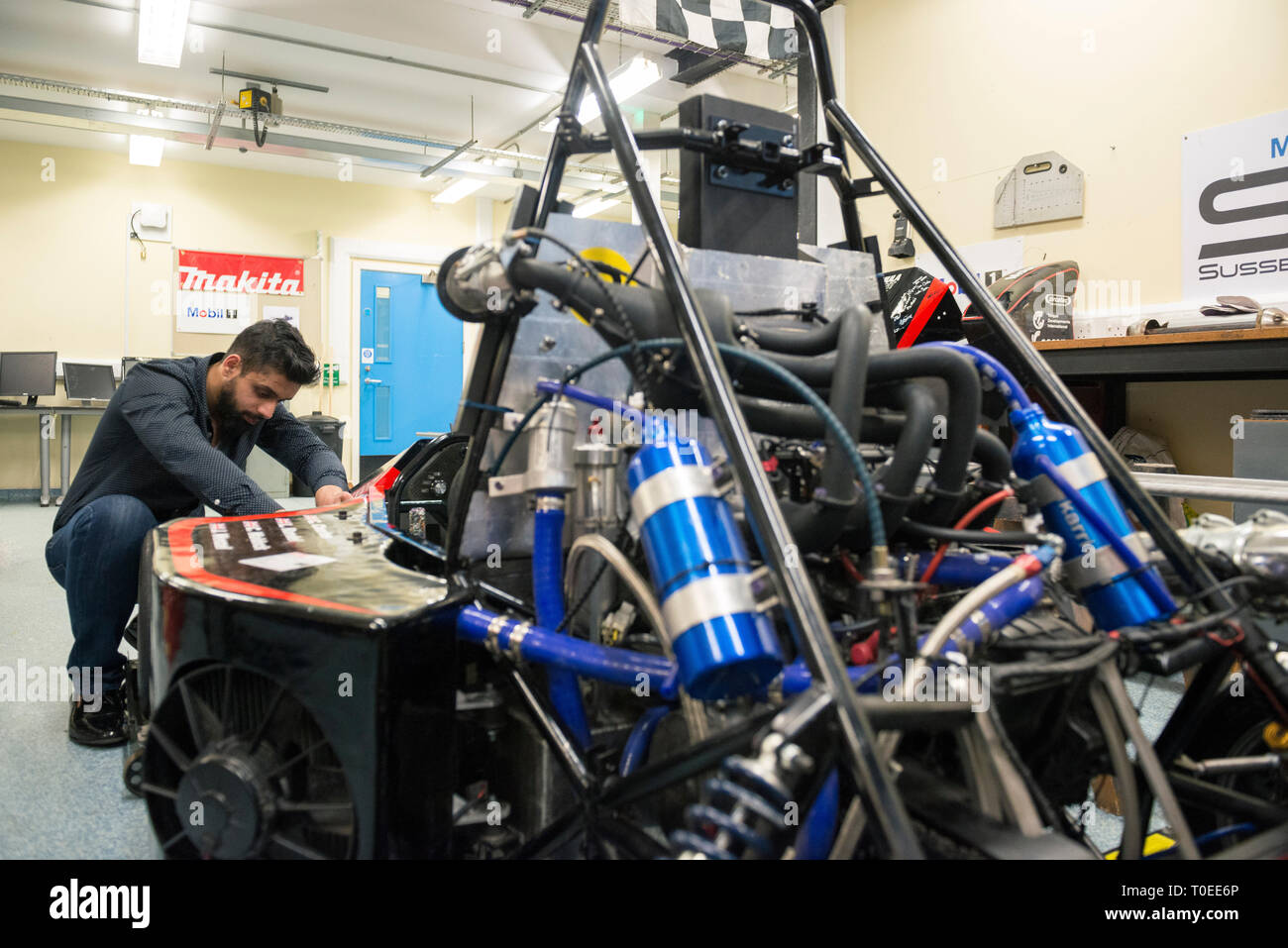 A young international muslim student woking on a racing motorsport cart ...