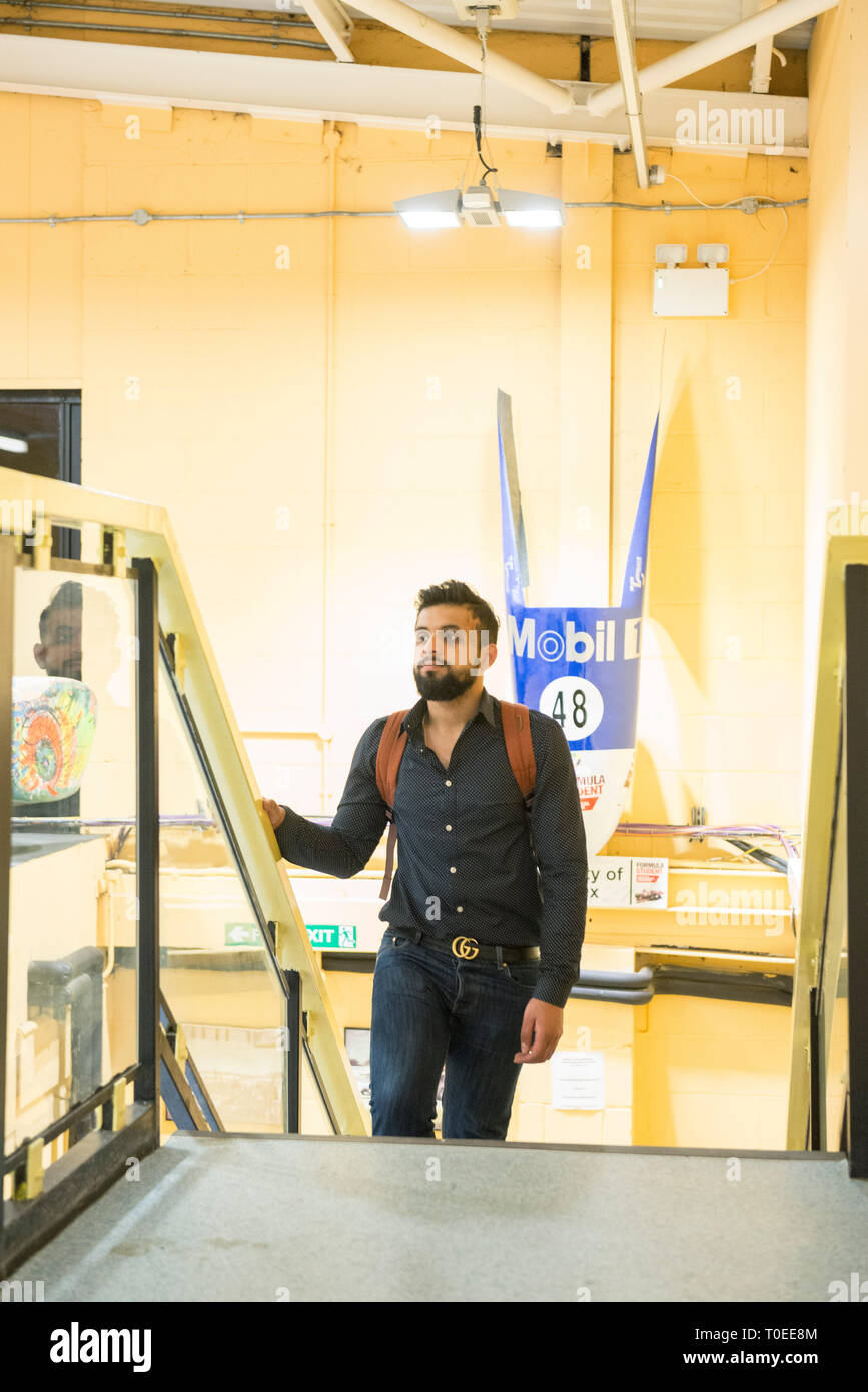 A young international muslim student woking on a racing motorsport cart ...