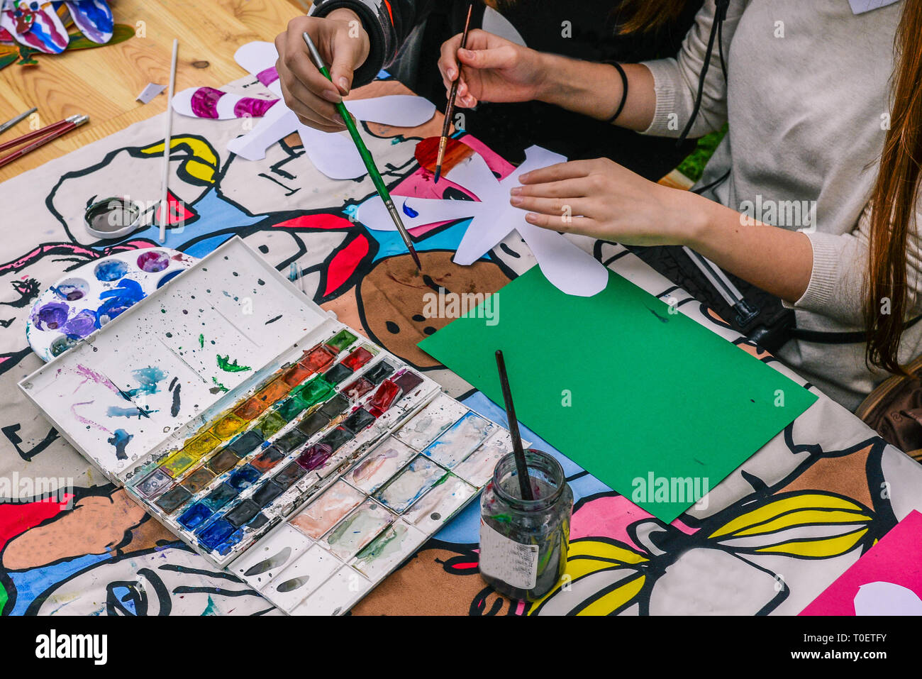 Girls paint colors at the table. In the hands of the brush. Color ...