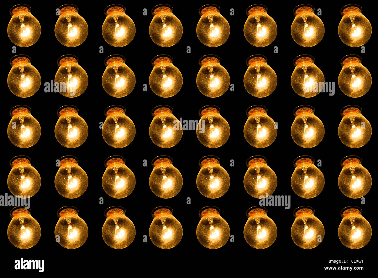 Glowing lamps on a black background. Many lamps in a row shine with ...
