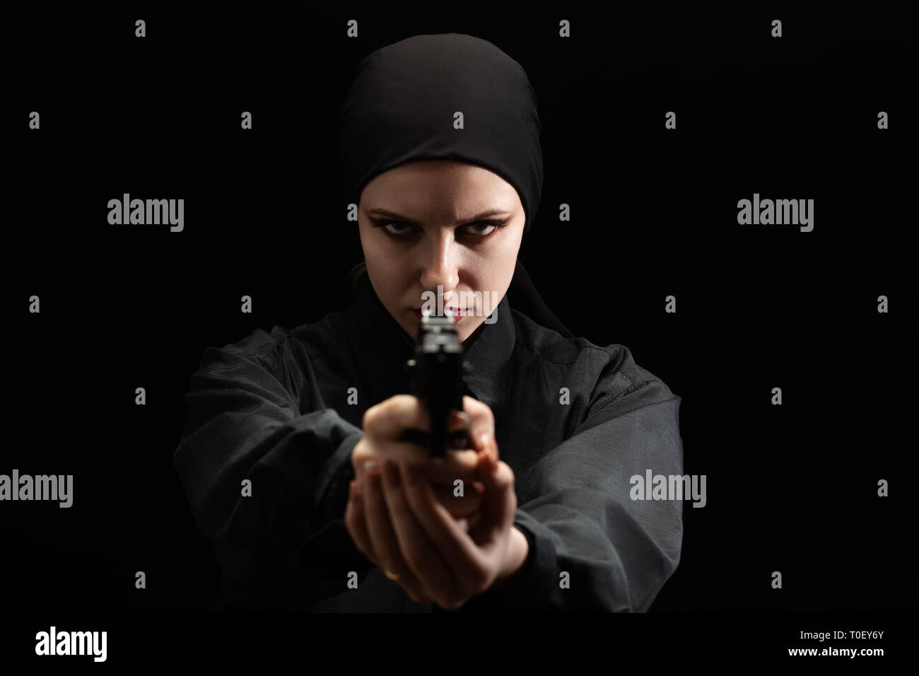 serious girl with gun aiming at camera on black background Stock Photo ...