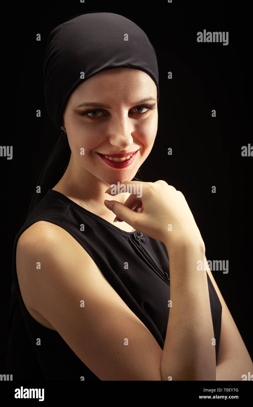 beautiful young woman in black headscarf n black background looking at ...