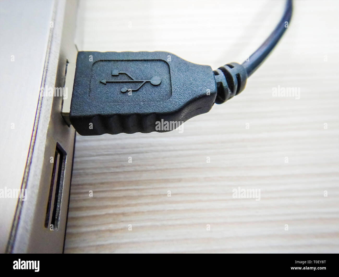 USB cable connecting to laptop computer close up - usb icon on cable ...