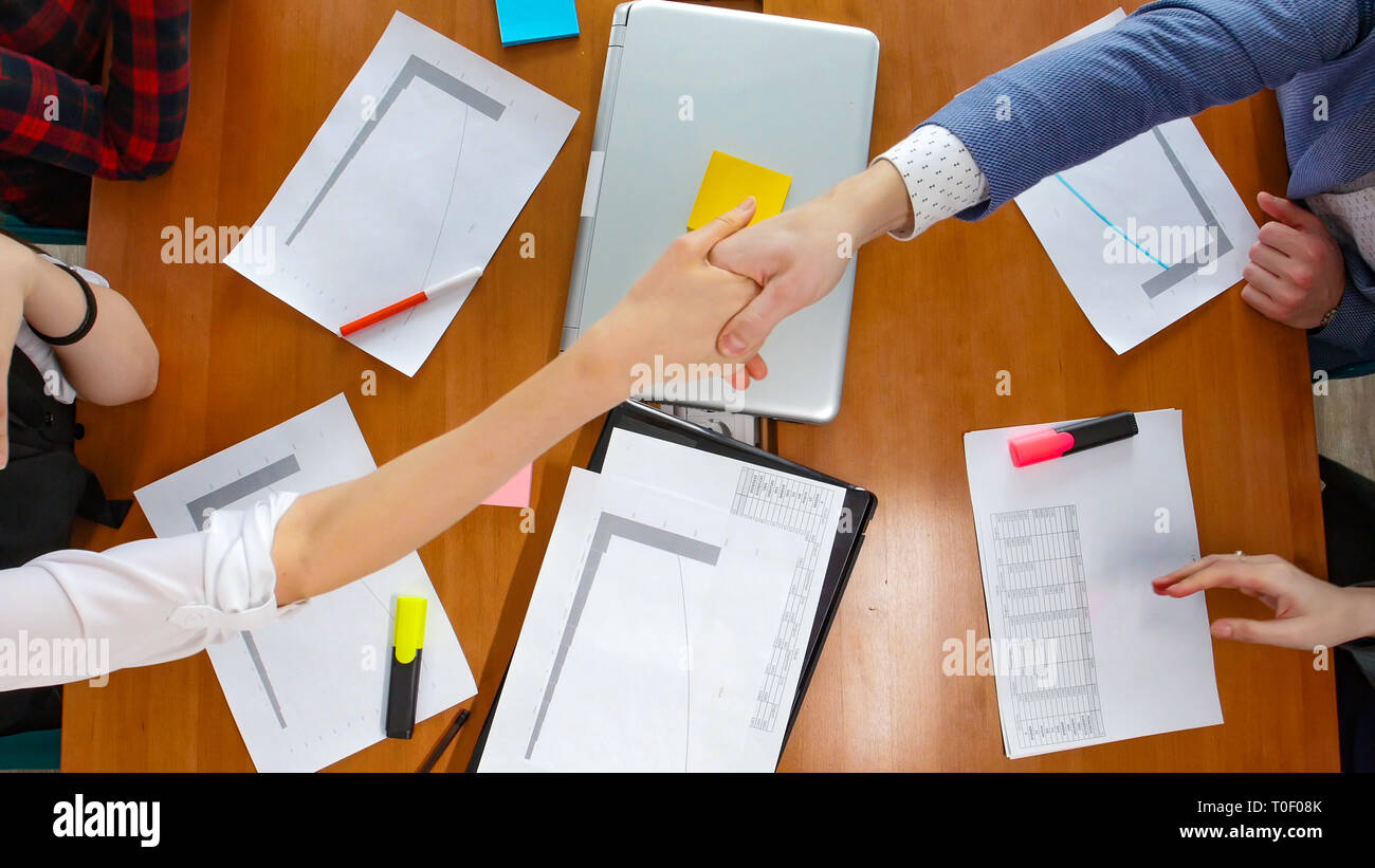 Business concept. People by table greeting each other with a handshake ...