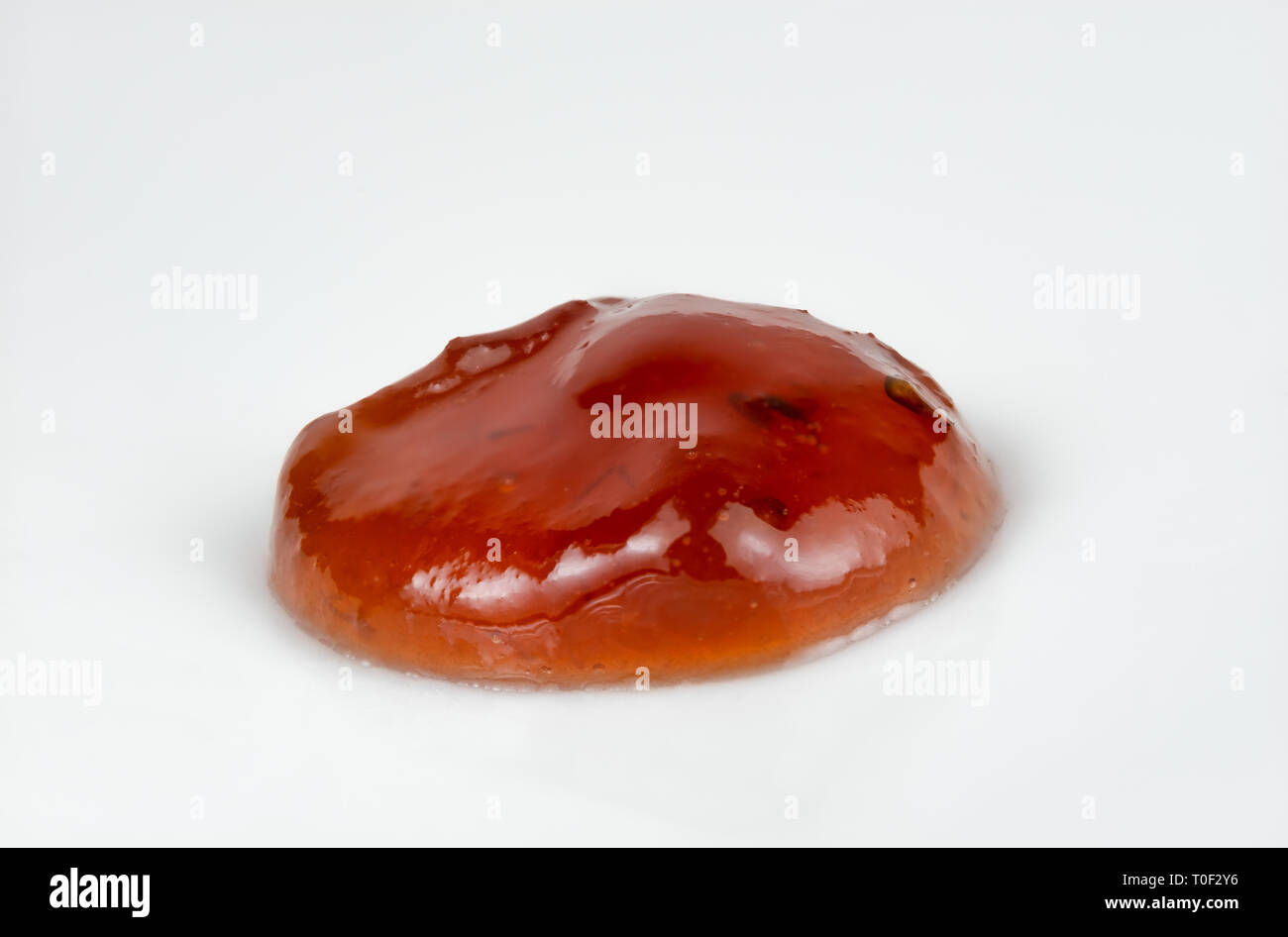 Macro image of a blob of strawberry jam against a white background ...