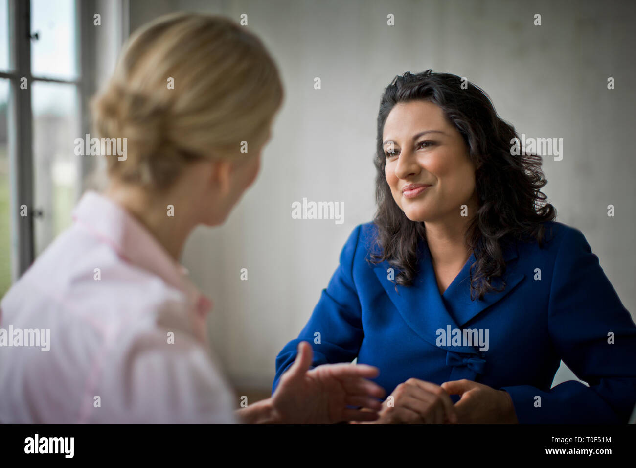 Two women smiling and talking Stock Photo - Alamy