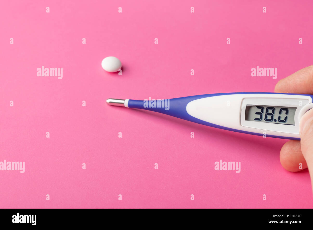 Electronic thermometer and pill on a pink background. High temperature ...