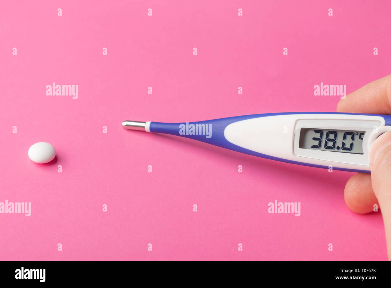 Electronic thermometer and pill on a pink background. High temperature ...