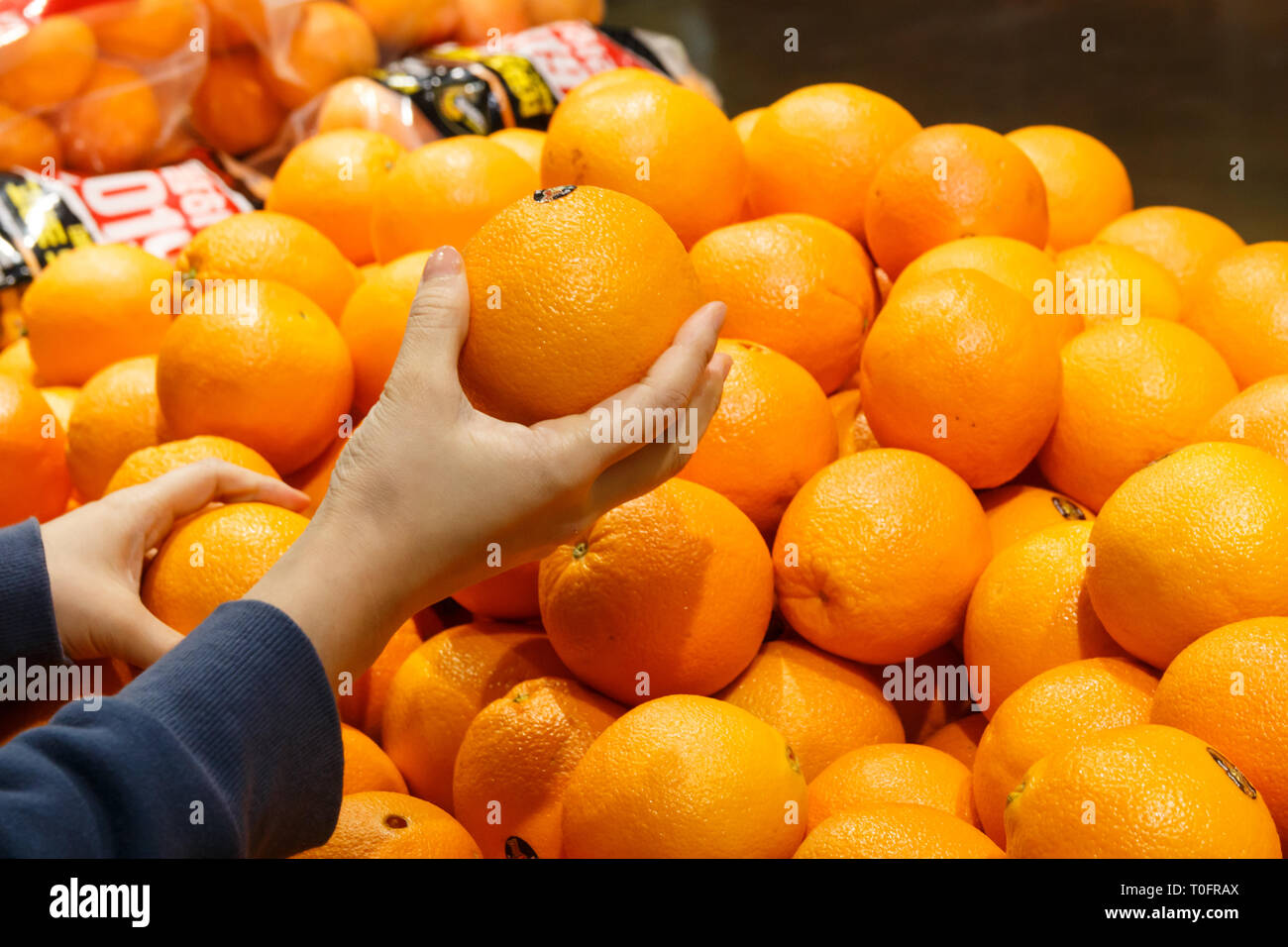 female hands pick up the orange in the grocery store Stock Photo - Alamy
