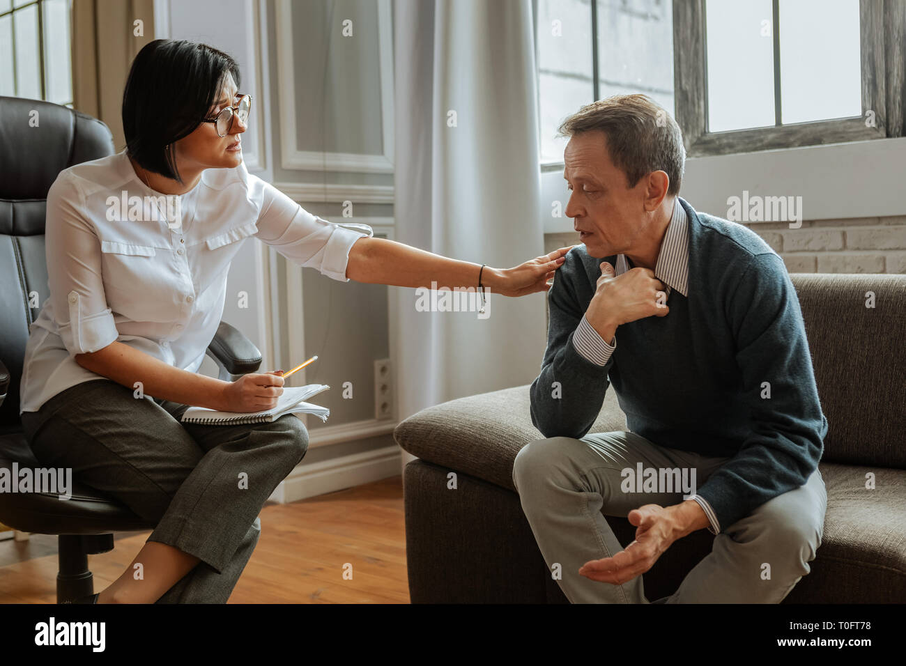 Caring Dark Haired Doctor Calming Her Patient Down During Session Stock