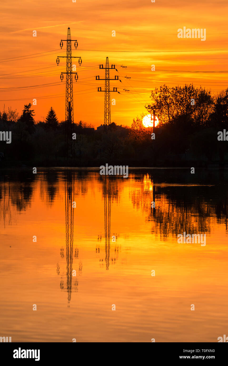 Electricity pylons on sunset background, reflection in a water Stock ...