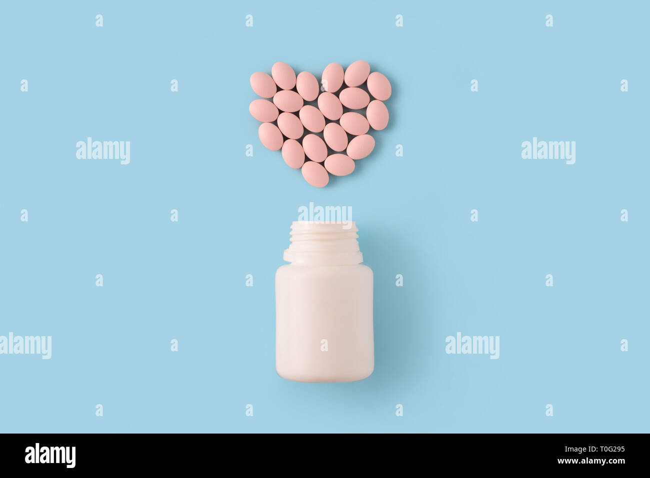 Pink pills in shape of heart and bottle on blue background. Medical ...