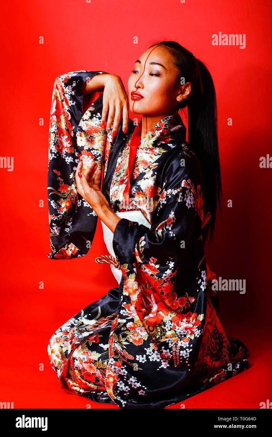 young pretty geisha on red background posing in kimono, oriental people ...