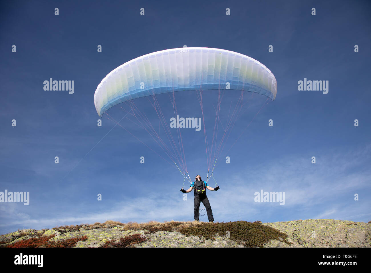 Paraglider Pilot stands on a slope and balances his paraglider above ...