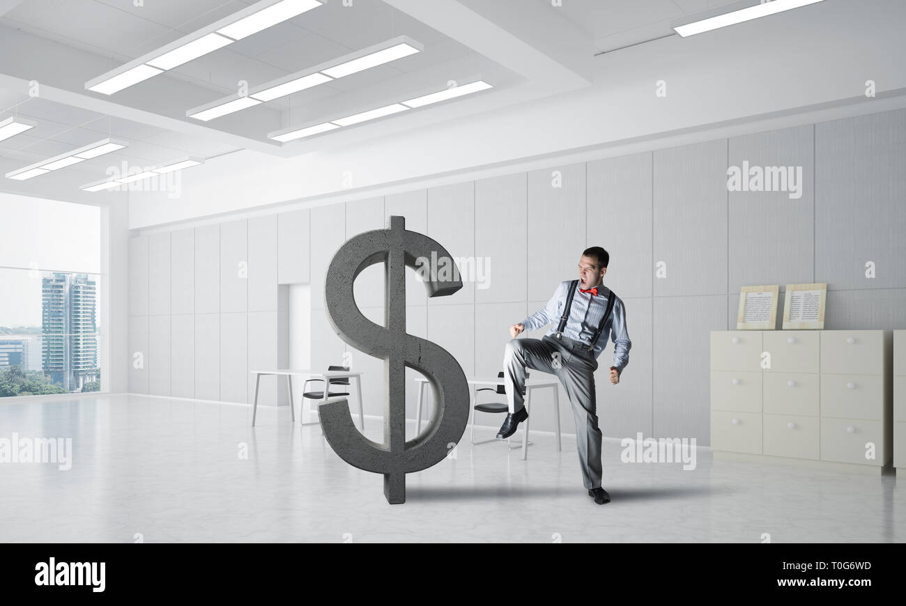 Determined banker man in modern office interior breaking dollar figure ...