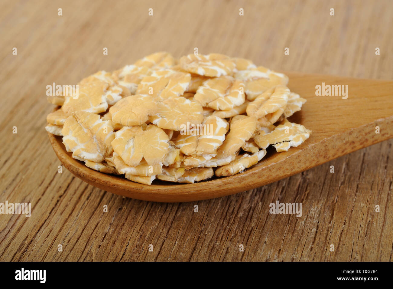 rolled wheat in wooden spoon Stock Photo - Alamy