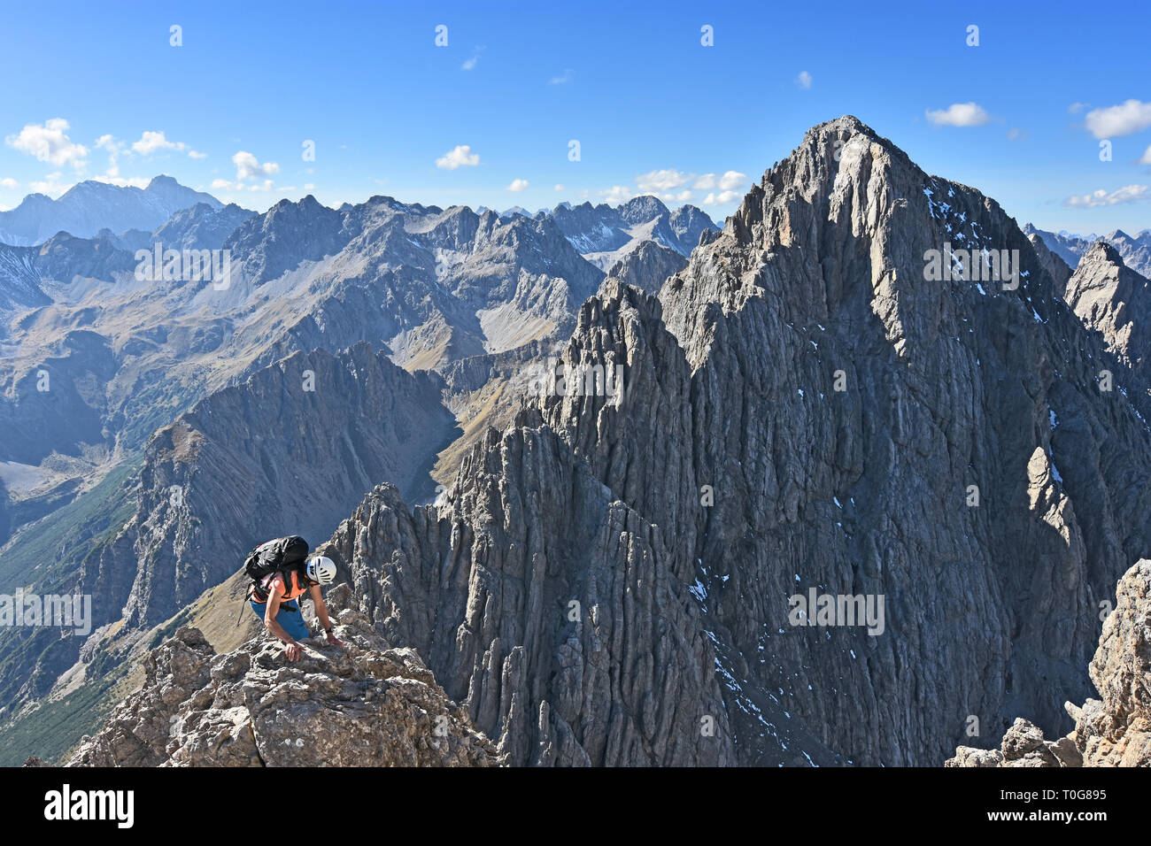 Woman climbing in a wild rocky landscape with steep mountains under ...