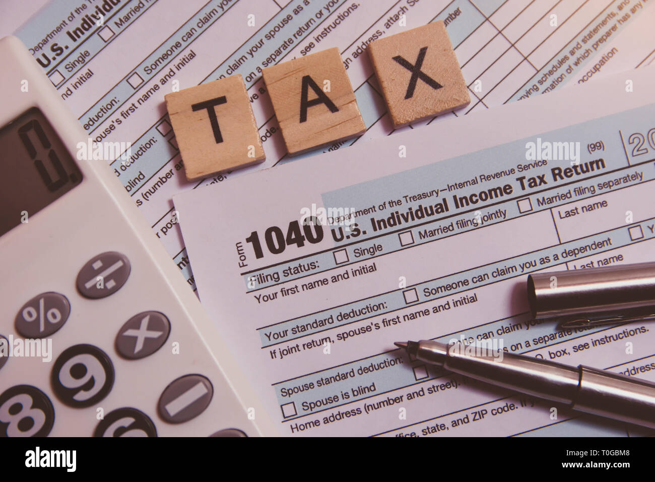 Tax with wooden alphabet blocks, calculator, pen on 1040 tax form ...