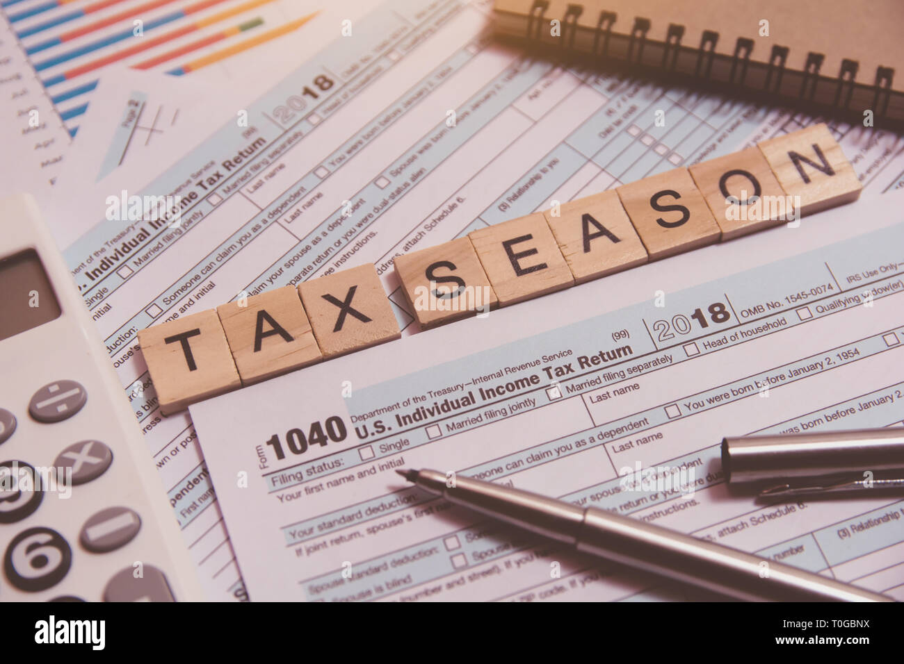 Tax season with wooden alphabet blocks, calculator, pen on 1040 tax ...