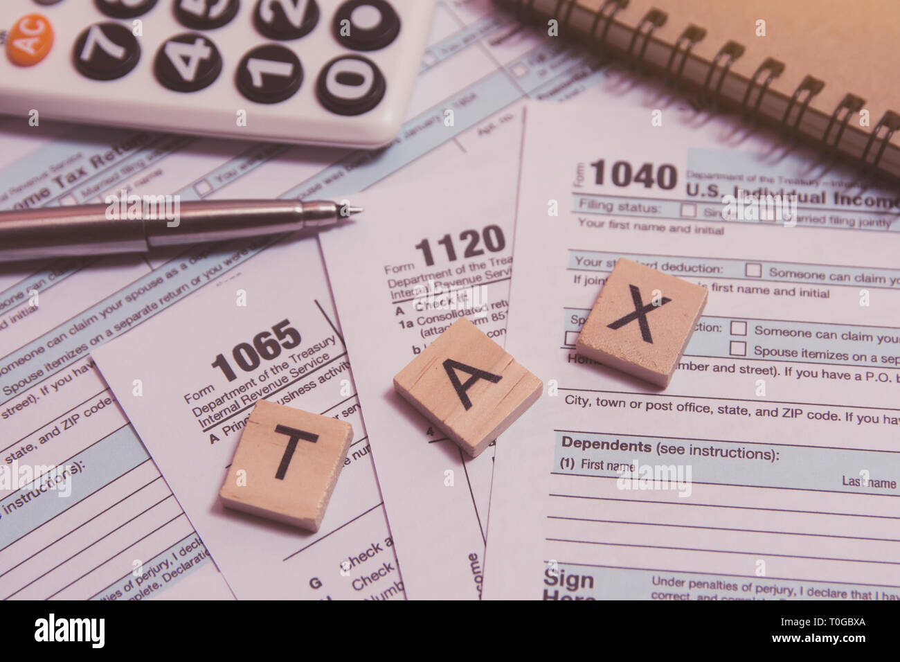 Tax with wooden alphabet blocks, calculator, pen on 1040 tax form ...