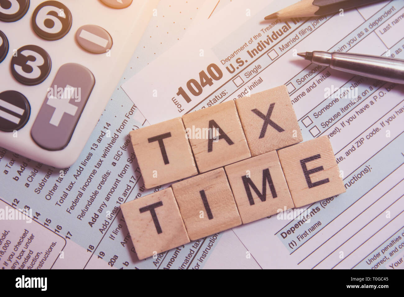Tax time with wooden alphabet blocks, calculator, pen on 1040 tax form ...