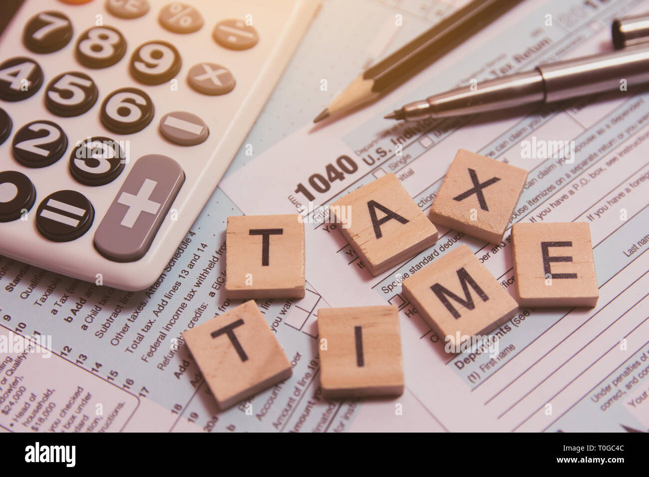 Tax time with wooden alphabet blocks, calculator, pen on 1040 tax form ...
