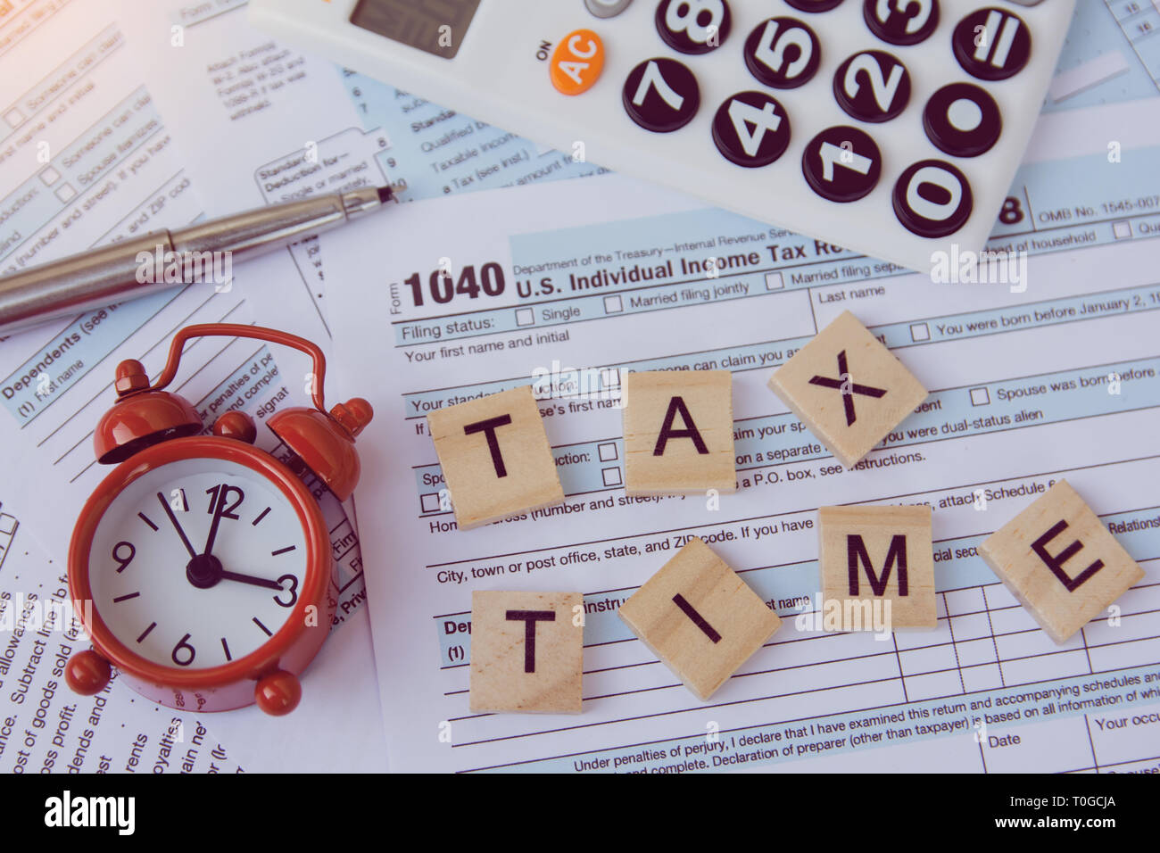Tax time with wooden alphabet blocks, red alarm clock, calculator and ...