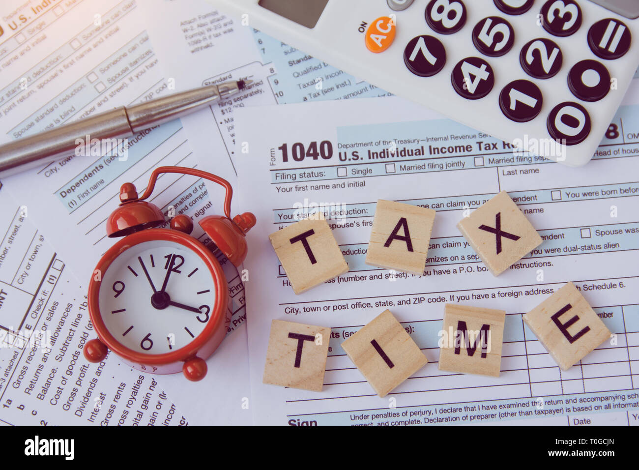 Tax time with wooden alphabet blocks, red alarm clock, calculator and ...
