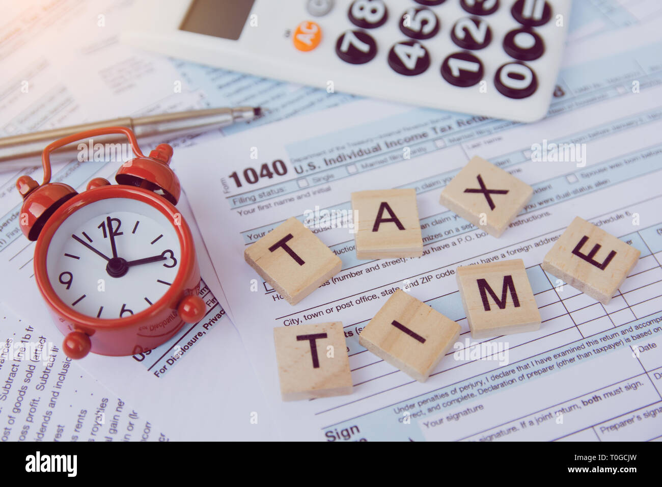 Tax time with wooden alphabet blocks, red alarm clock, calculator and ...