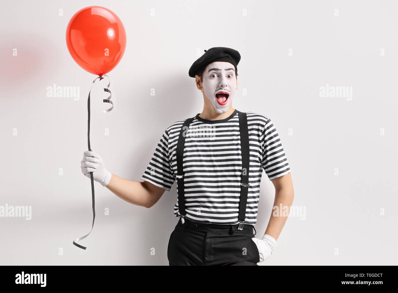 Mime holding a red balloon and leaning against a wall Stock Photo - Alamy