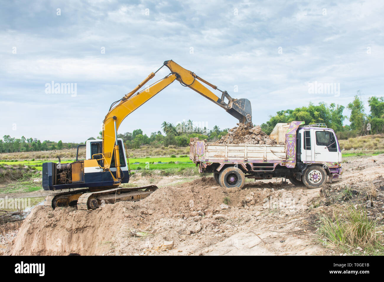 Yellow excavator machine loading soil into a dump truck at construction ...
