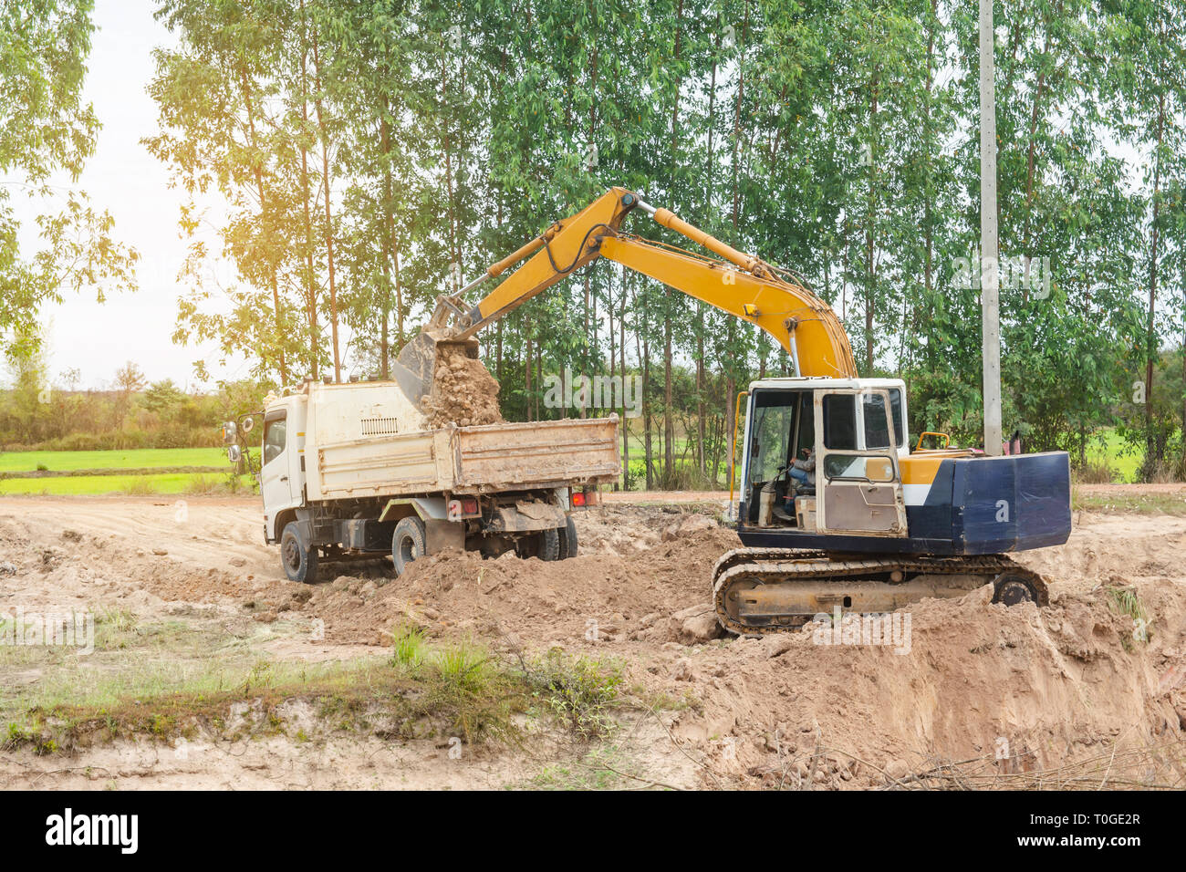 Yellow excavator machine loading soil into a dump truck at construction ...