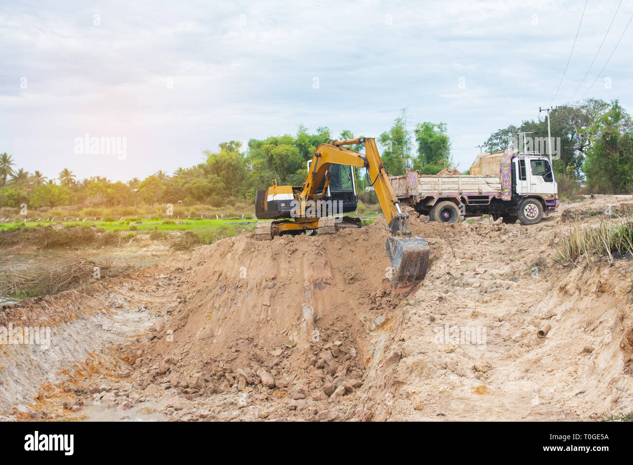 Yellow excavator machine loading soil into a dump truck at construction ...