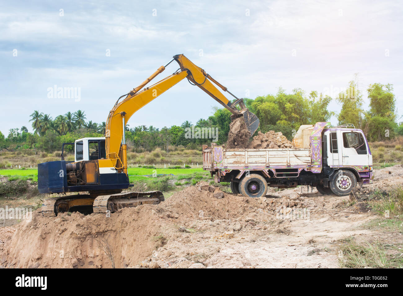 Yellow excavator machine loading soil into a dump truck at construction ...