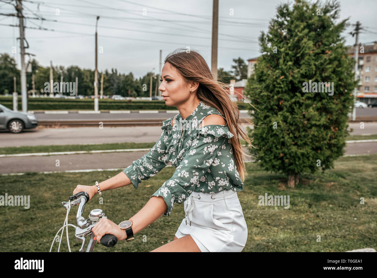 Girl in the summer in city, riding a bike, against the backdrop of ...