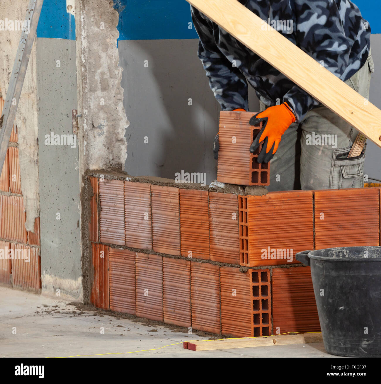 Bricklayer industrial worker installing brick masonry on interior wall ...