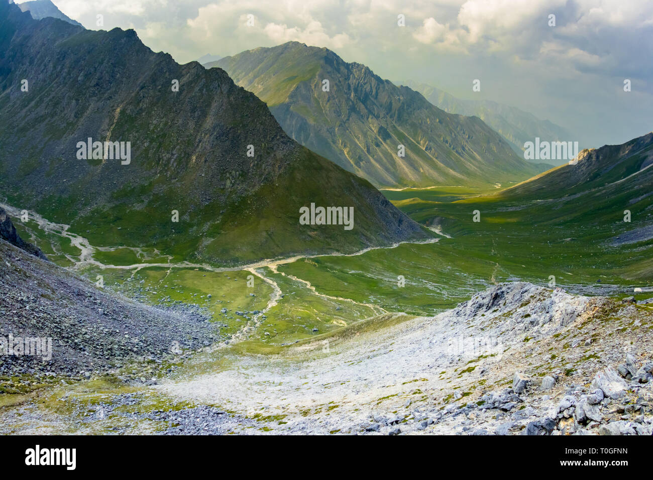 Landscape river flows in a mountain valley in the summer in the clouds ...
