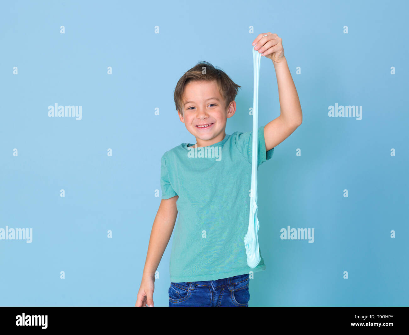 cool, pretty boy plays with homemade slime in front of a blue ...