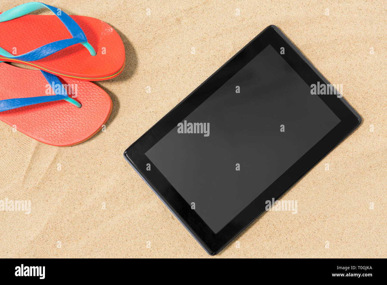 tablet computer and flip flops on beach sand Stock Photo - Alamy