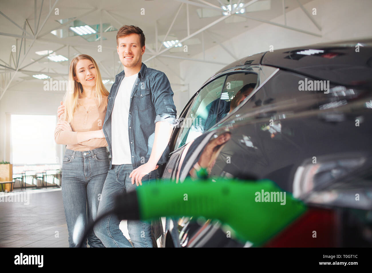 Young smiling family buying first electric car in the showroom ...