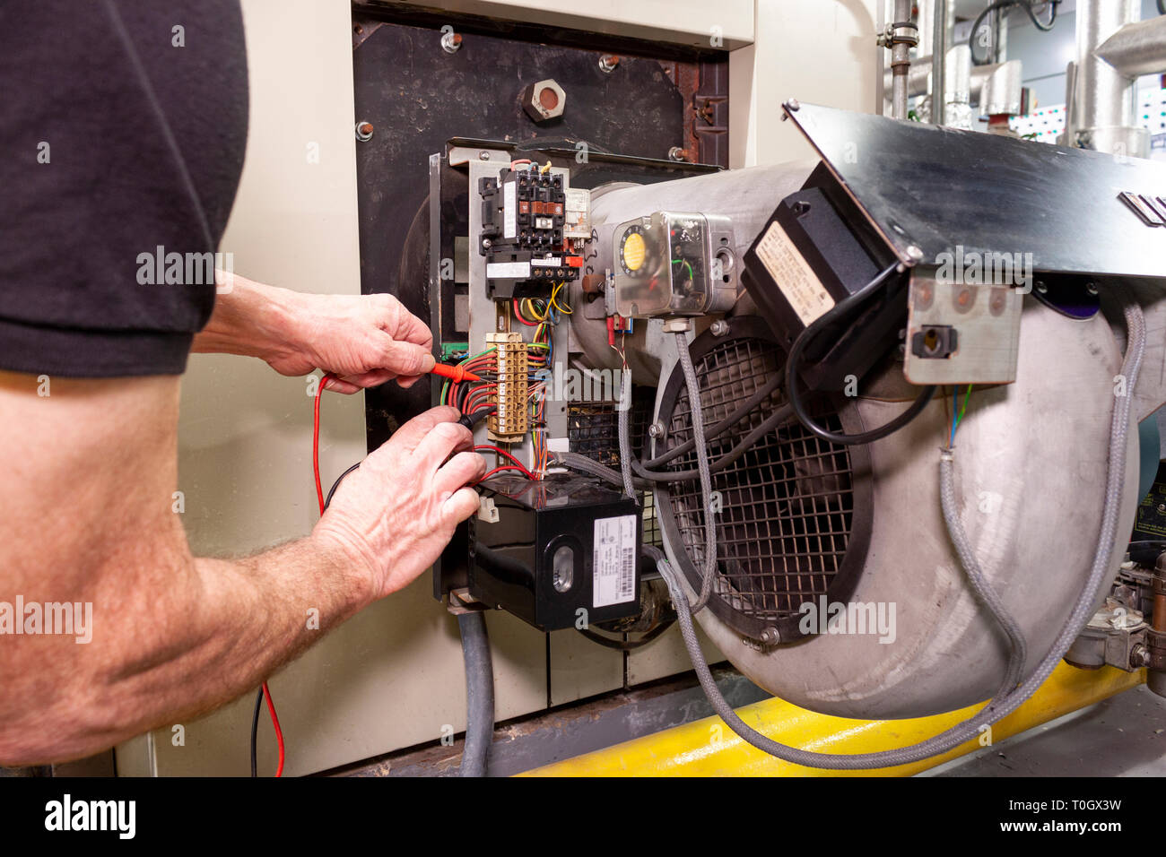 Industrial boiler engineer using an electrical tester to check circuit ...