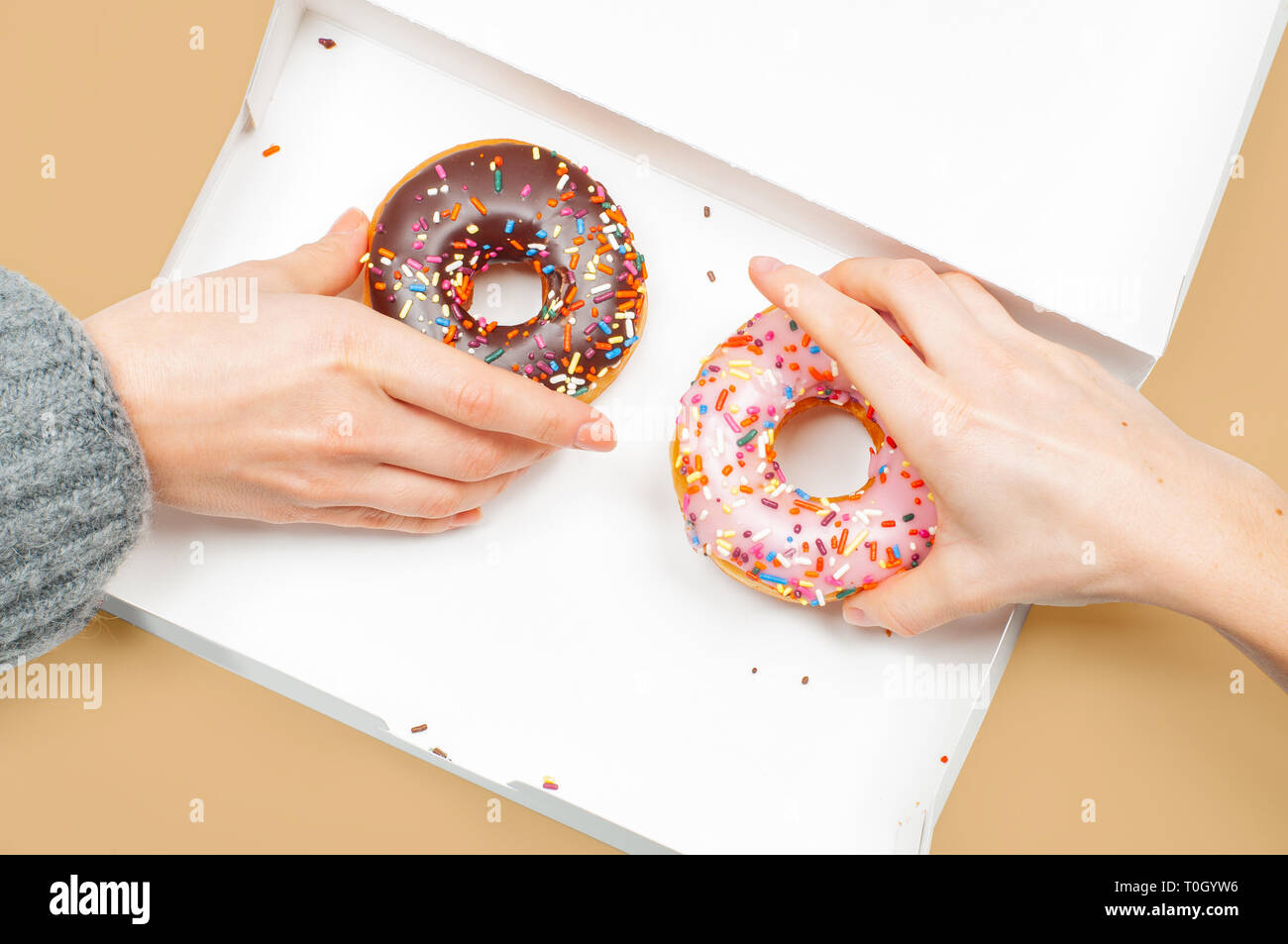 Female hands is taking colorful donuts. Hands is grabbing two last ...