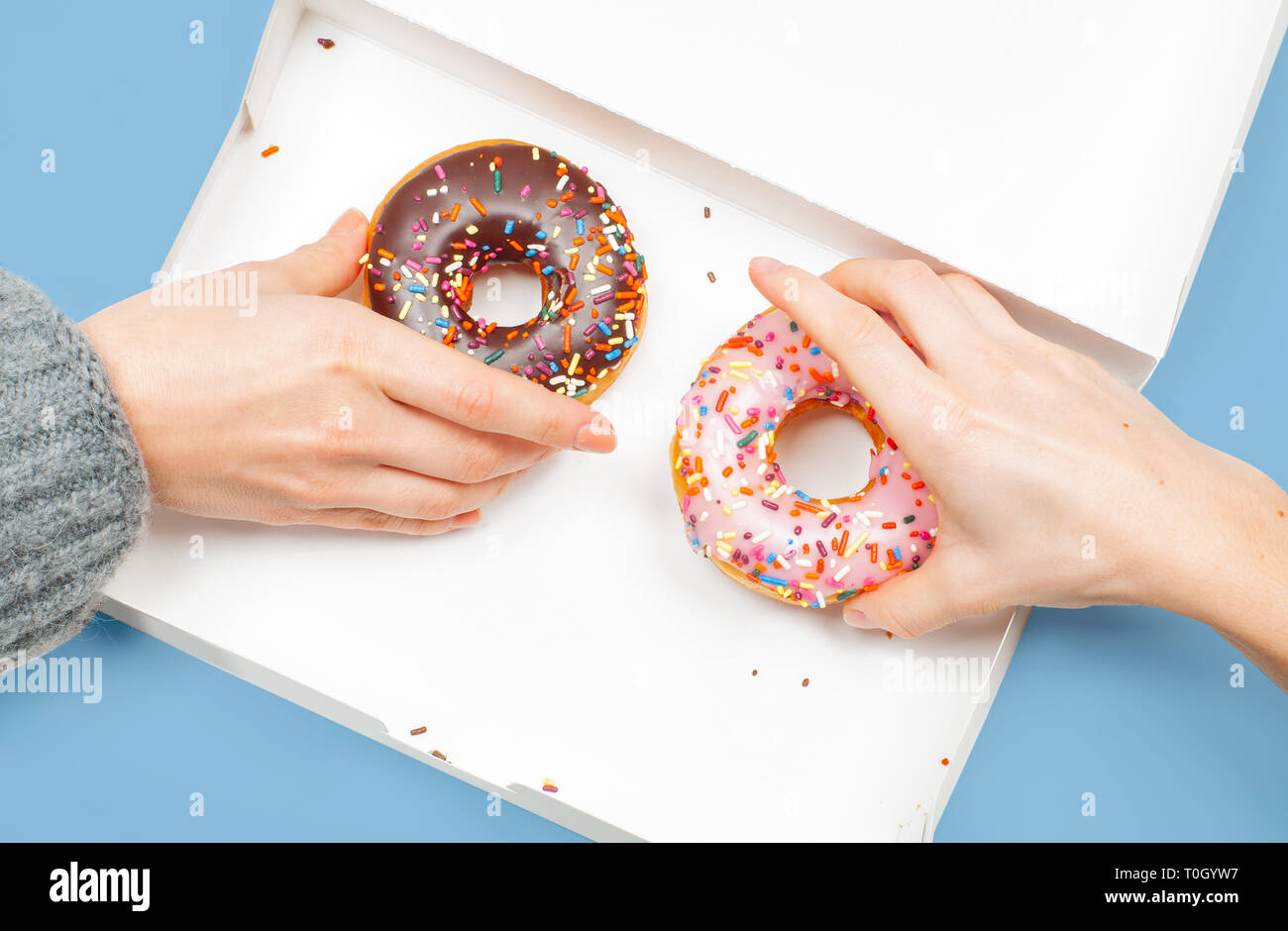 Female hands is taking colorful donuts. Hands is grabbing two last ...
