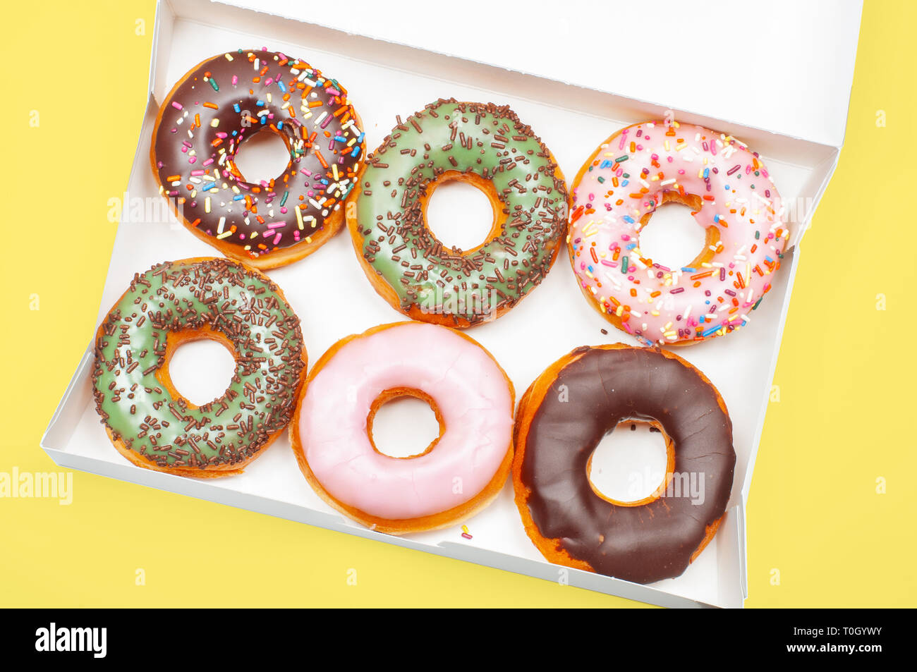 Colorful donuts in box on pastel yellow background Stock Photo - Alamy