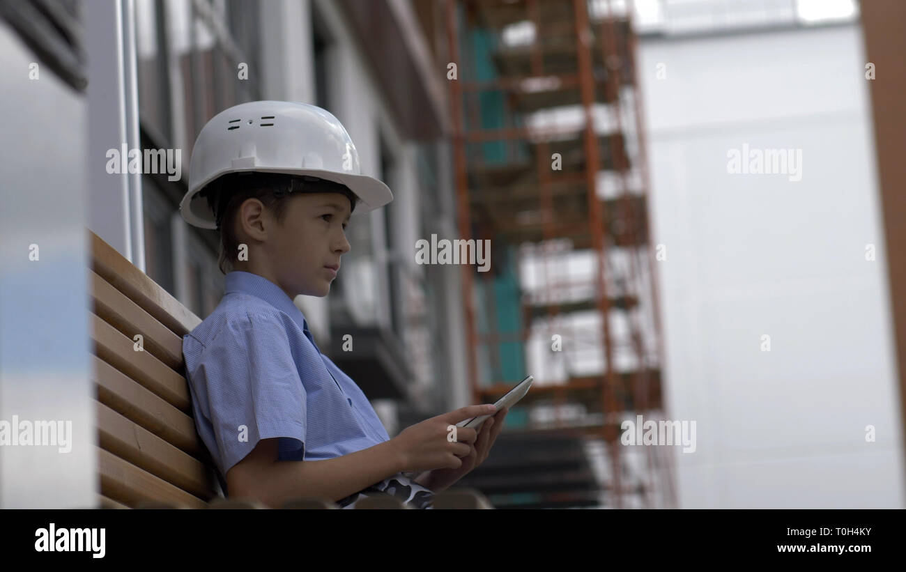 boy builder sits on the bench uses a tablet, monitors the builder ...