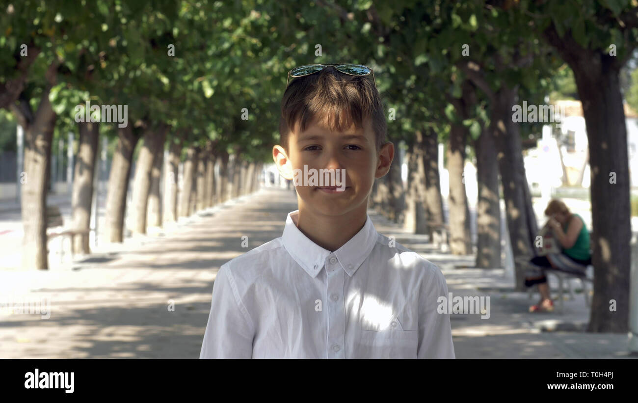 portrait of a funny boy looking at the camera on the street, have fun ...