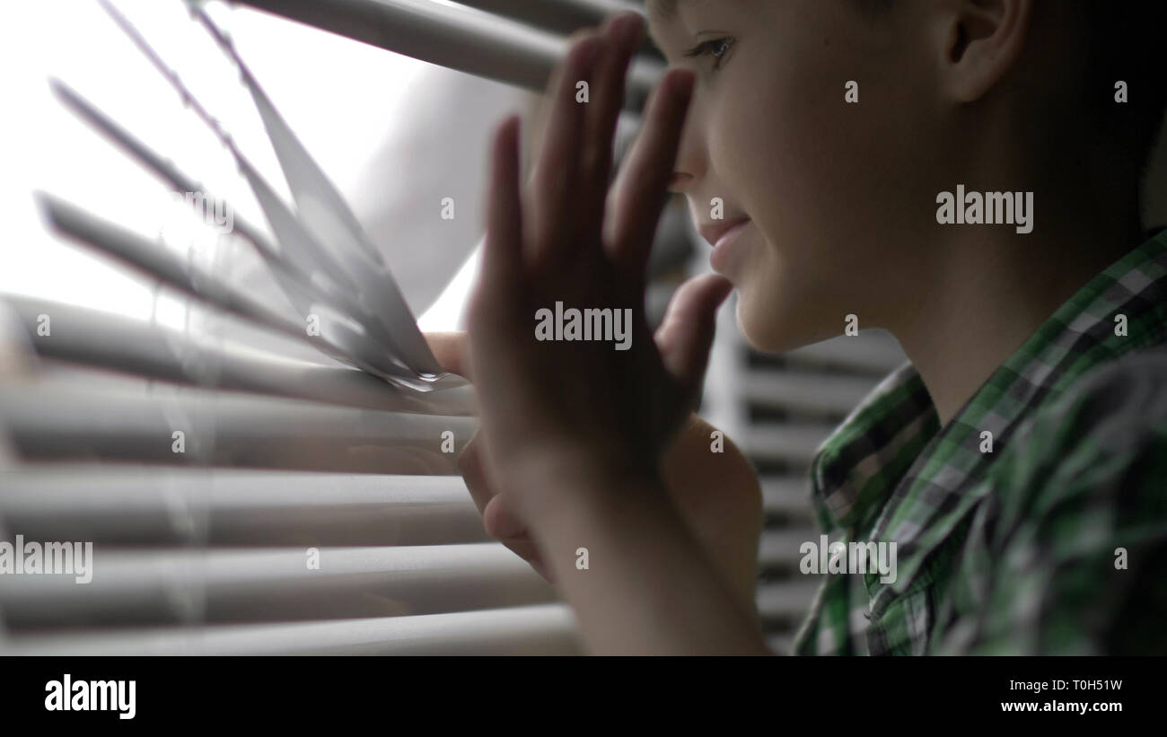 boy looks out the window and waves his hand to someone, welcomes, have ...
