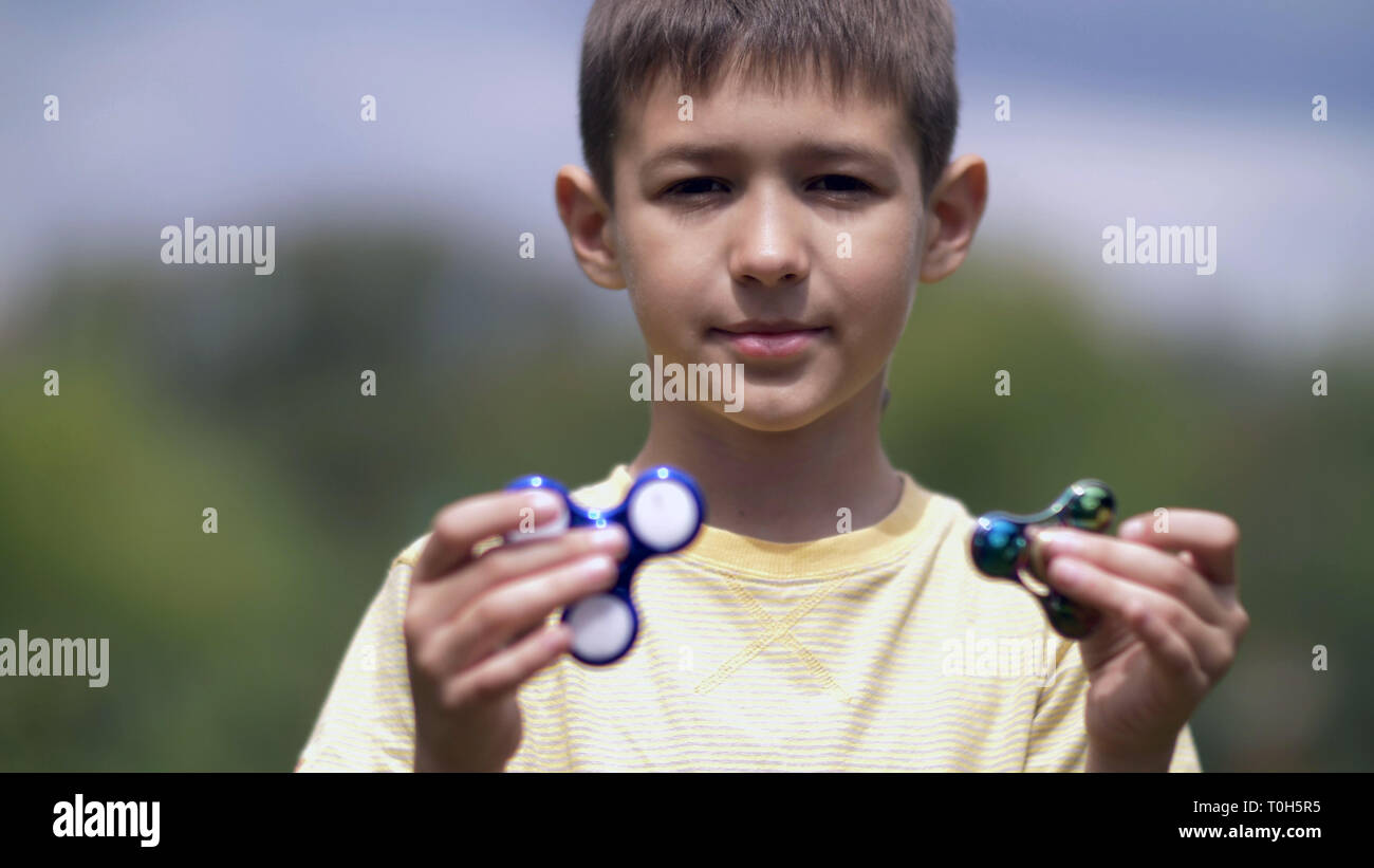 Happy Boy holding play two fidget spinners on nature Stock Photo - Alamy