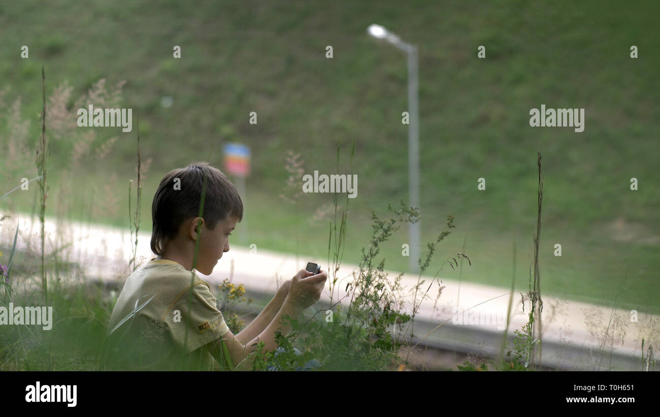 boy hiding and playing in the phone outoors, back view Stock Photo - Alamy