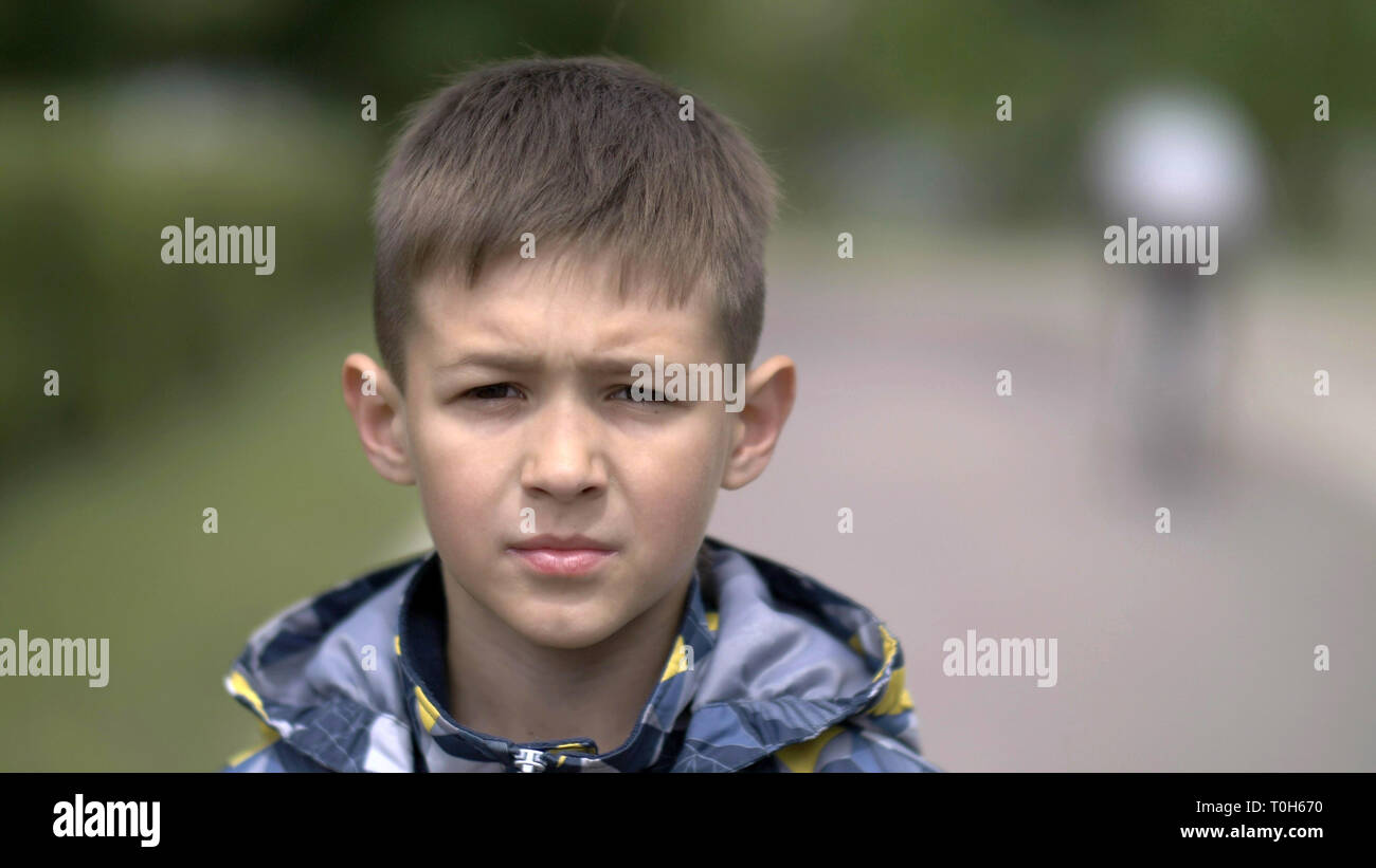 portrait of a serious boy with a tence glance looking at the camera ...